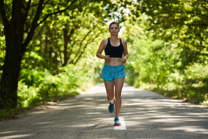 Woman Running through Forest on Asphalt Stock Photo - Image of girl, people: 289323906