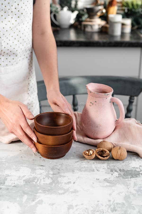 Woman`s Hands in an Apron Put on the Table with a Jug a Stack of Wooden ...