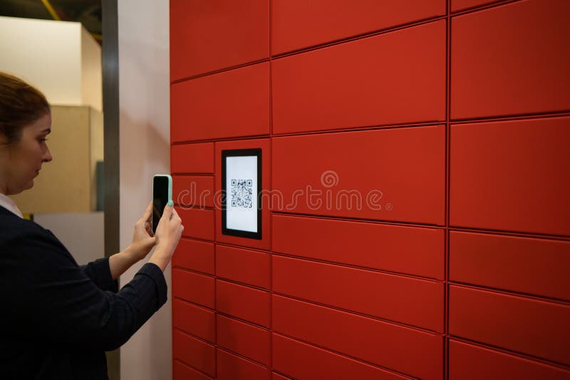 A Woman Scans a Red Code To Pick Up a Parcel at a Parcel Machine ...