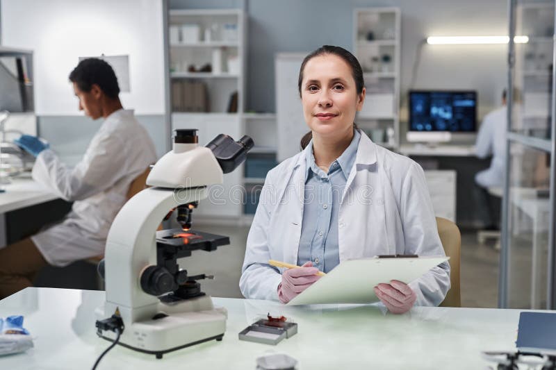 Woman Scientist Looking at Camera Working with Microscope in Laboratory Stock Image - Image of ...