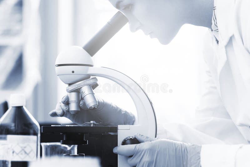 Woman Scientist is Using Microscope in a Laboratory during Research ...