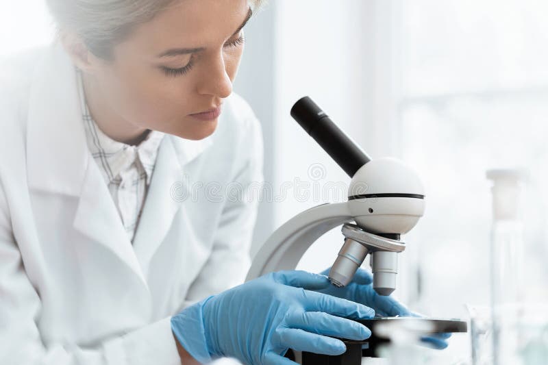 Woman Scientist is Using Microscope in a Laboratory during Research ...