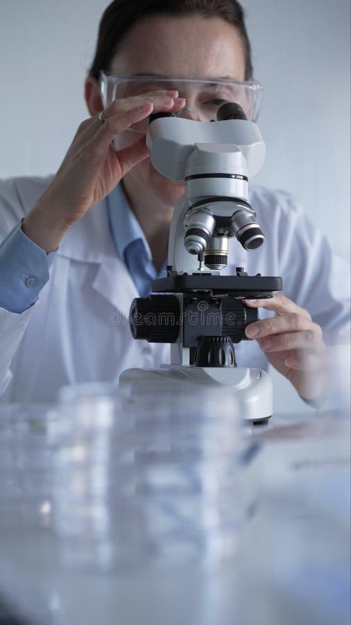 Woman Scientist Wearing Lab Coat and Protective Glasses is Using ...