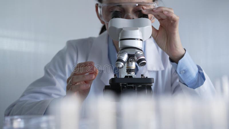 Woman Scientist Wearing Lab Coat and Protective Glasses is Using ...