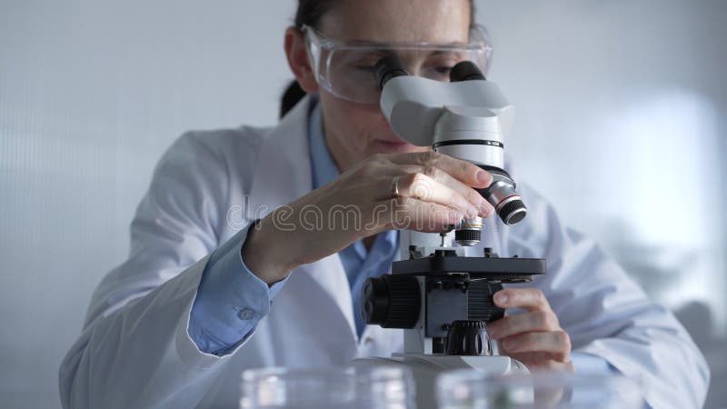 Woman Scientist Wearing Lab Coat and Protective Glasses is Using ...