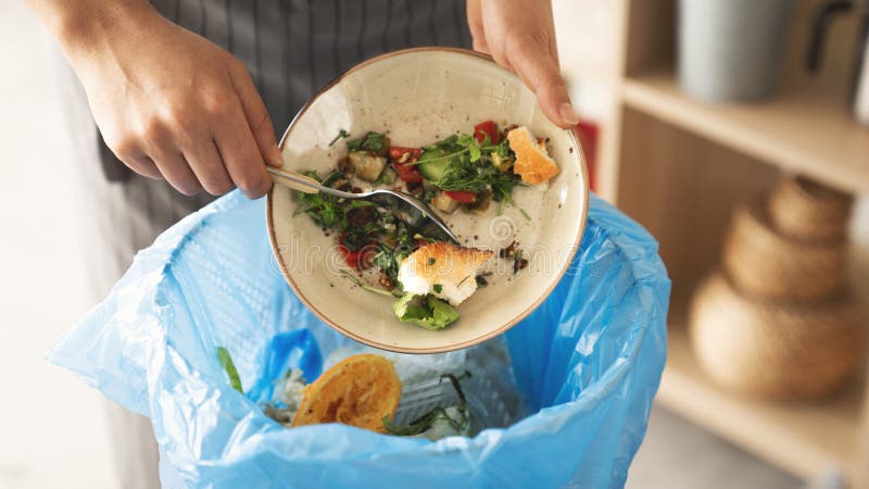 Woman Scraping Leftover Food from Plate into Trash Bin in Kitchen Stock ...