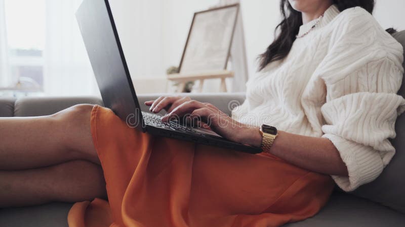 Woman is Seated on a Couch Using a Laptop Computer with Her Fingers ...