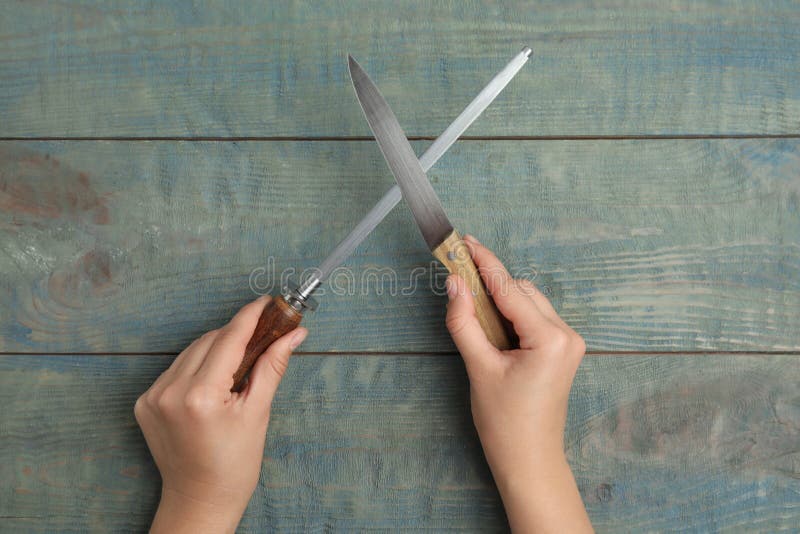 Woman Sharpening Knife at Light Blue Wooden Table, Top View Stock Photo ...