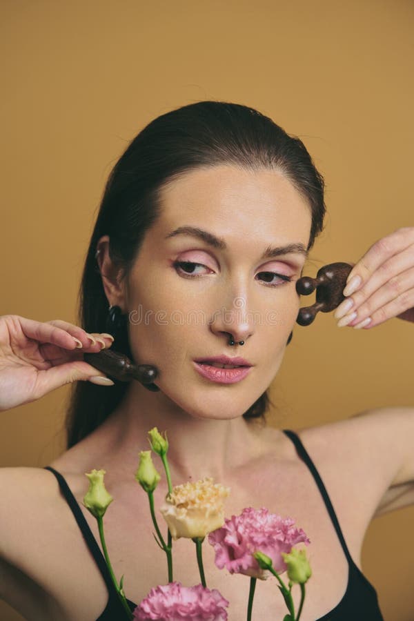 Woman Holding Figurines while Posing with Flowers in a Studio Setting ...