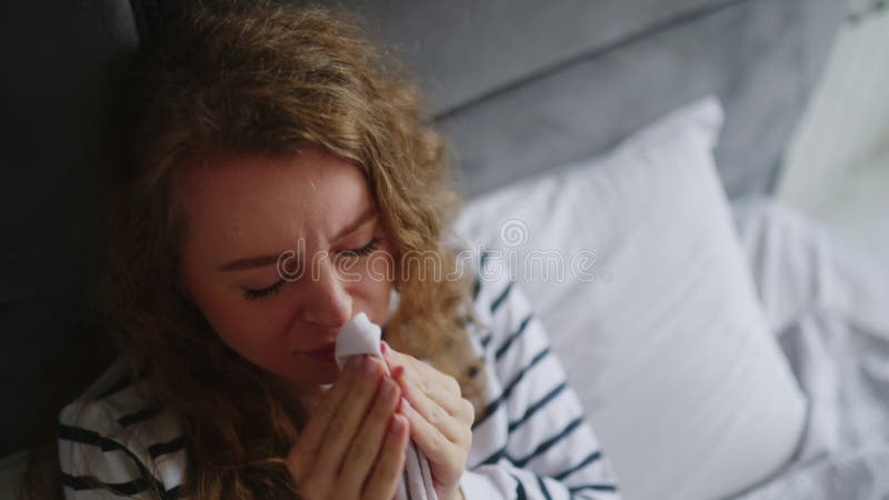 Woman Sick With Flu Coughing And Blowing Her Nose On Her Bed At Home