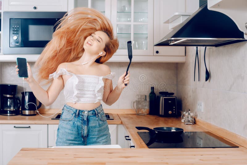 Woman Singing And Dancing In The Kitchen With A Smartphone Music A