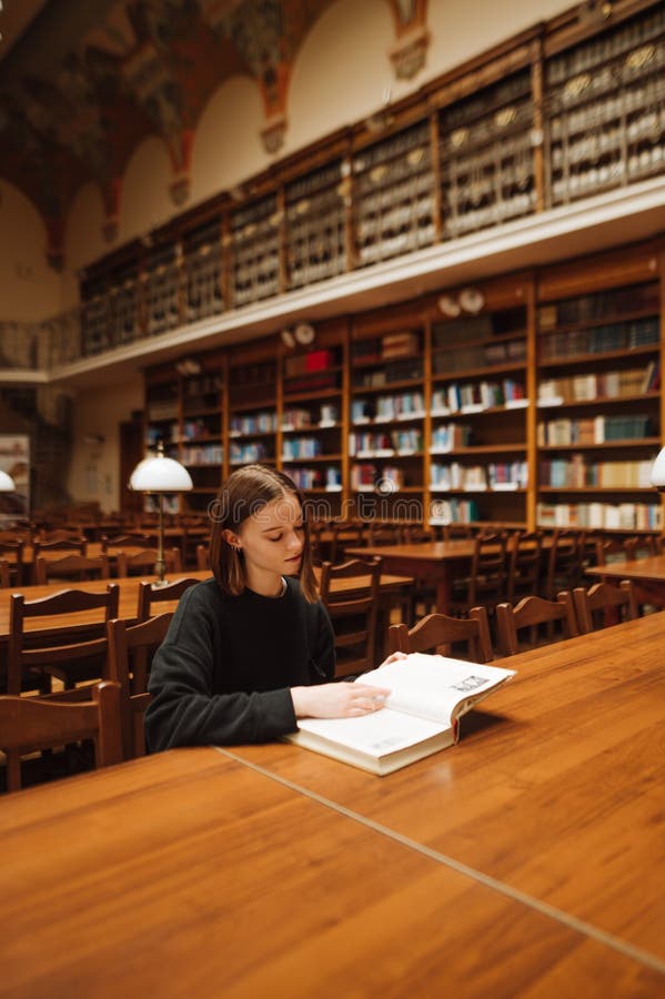 Woman Sits Alone in a Beautiful Old Public Library at a Table and Reads ...