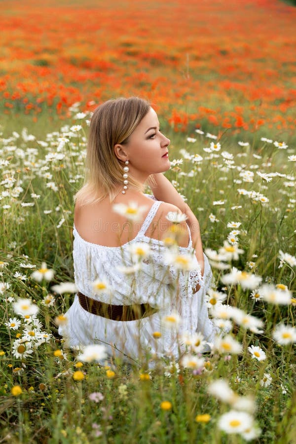 A Woman Sits in a Chamomile Field, Dressed in a White Dress Stock Photo ...