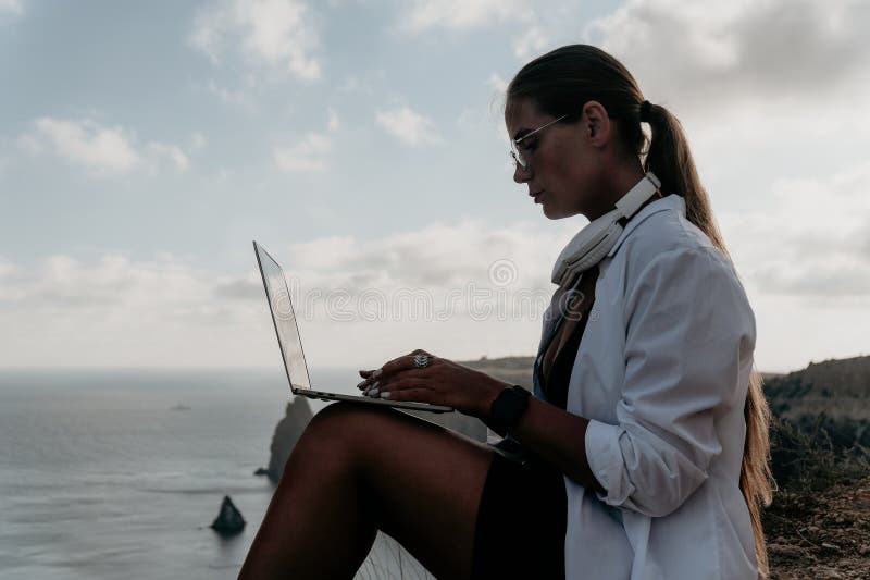 Woman Laptop Cliffside Working Remotely: a Woman Sits on a Cliffside ...