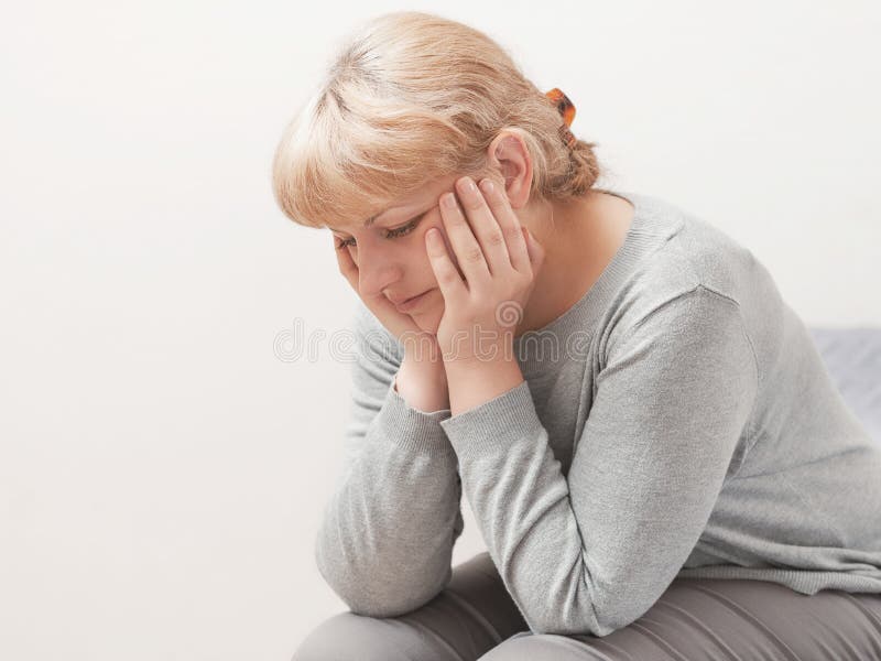 A Woman Sits with Her Head Down, Her Head Resting on Her Hands, Looking ...