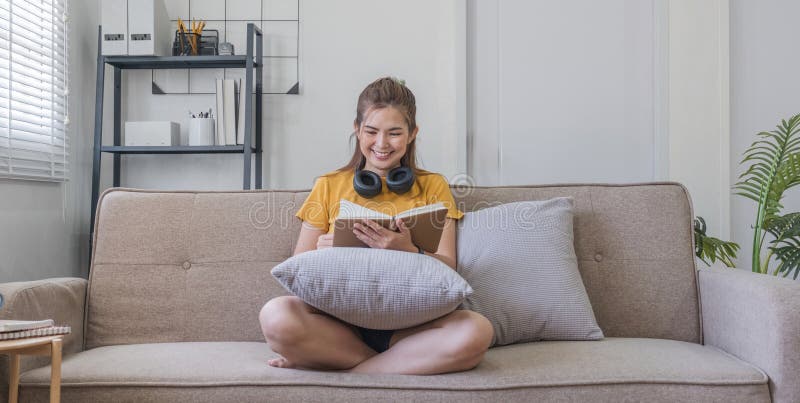 A Woman Sits on a Sofa Reading a Novel on Her Lap. Stock Photo - Image ...