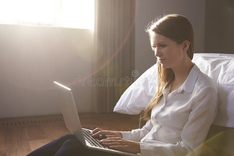 Woman Sitting on Bed in Bedroom Using Laptop Computer Stock Photo ...