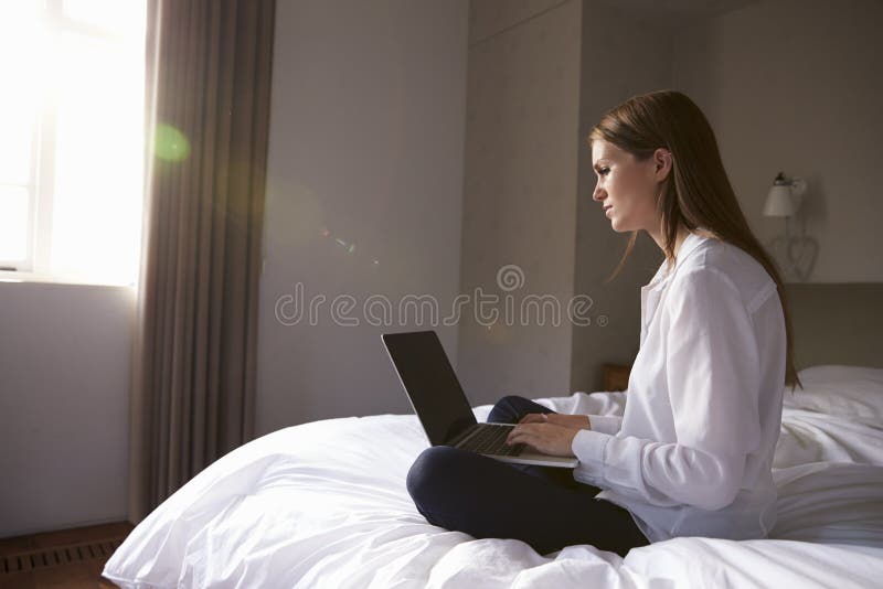 Woman Sitting on Bed in Bedroom Using Laptop Computer Stock Image ...