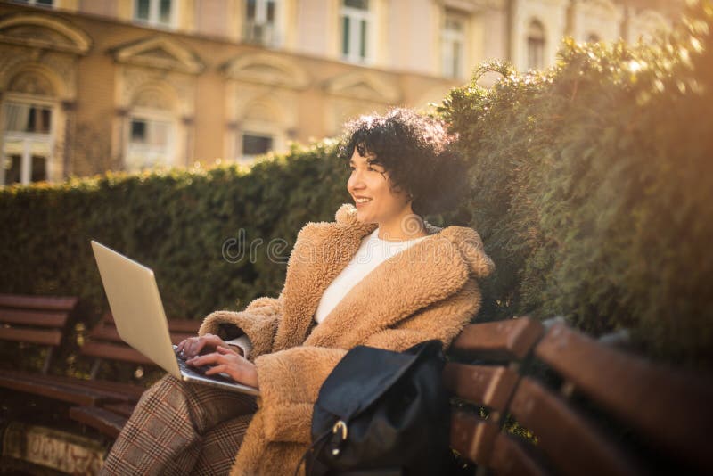Young Woman Sitting on Bench and Working on Laptop Stock Image - Image ...