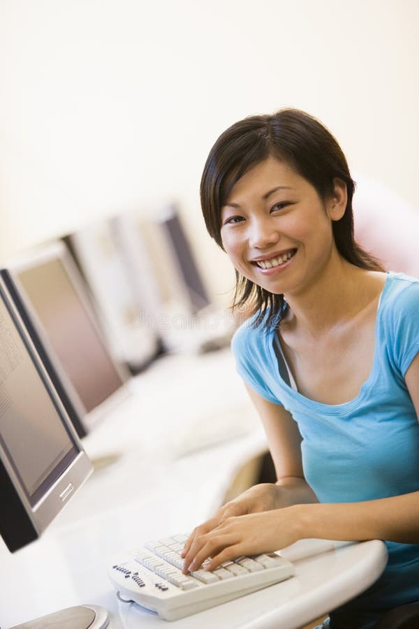 Woman Sitting in Computer Room Typing and Smiling Stock Photo - Image ...
