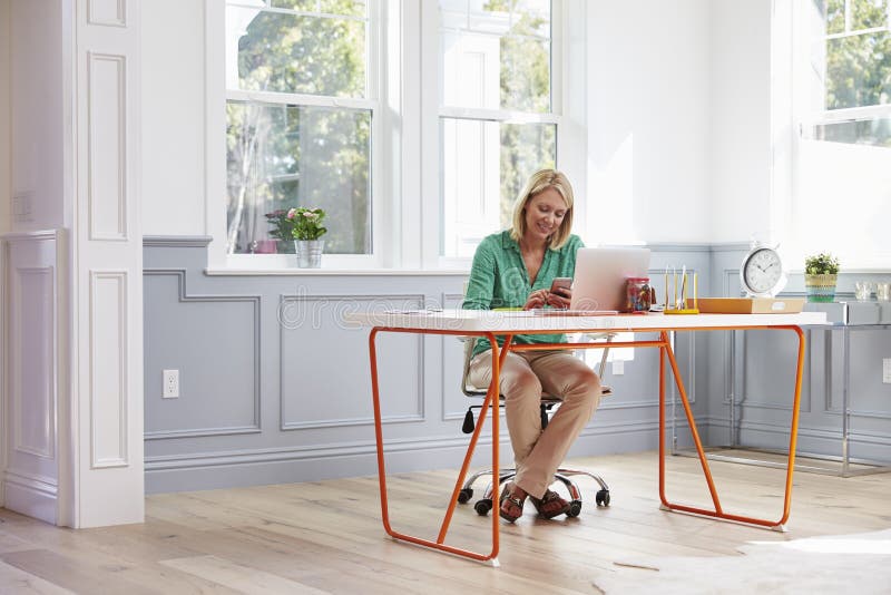 Woman Sitting at Desk Using Mobile Phone in Home Office Stock Photo ...