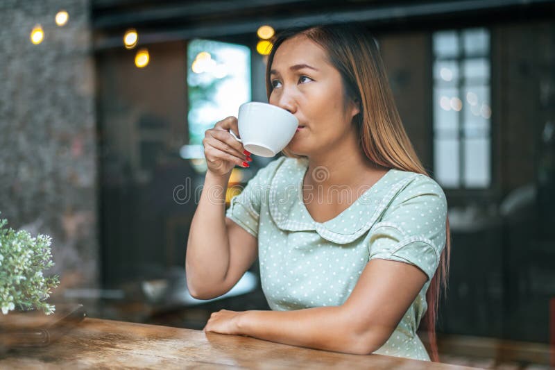 A Woman Sitting and Drinking Coffee in a Coffee Shop Stock Photo ...