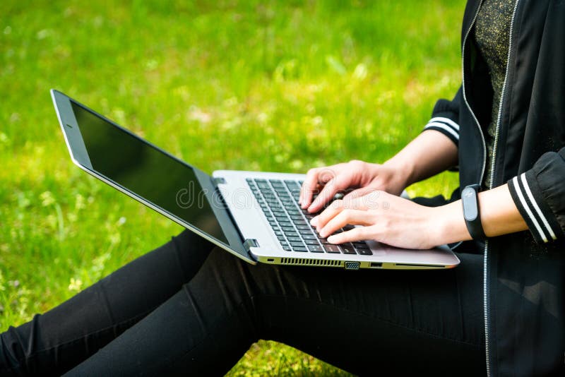 A Woman is Sitting on the Grass while Using Laptop Computer Stock Photo ...
