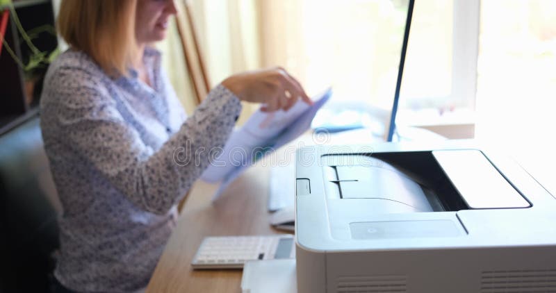 A Woman Sitting in the Office Prints Out Reports on the Printer Stock ...