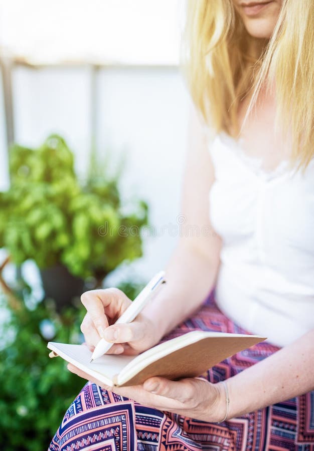 Woman Sitting on Patio Taking Notes in Notebook Stock Image - Image of ...