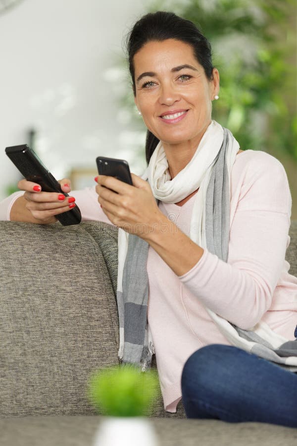Woman Sitting on Sofa with Cellphone and Tv Control Stock Image - Image ...