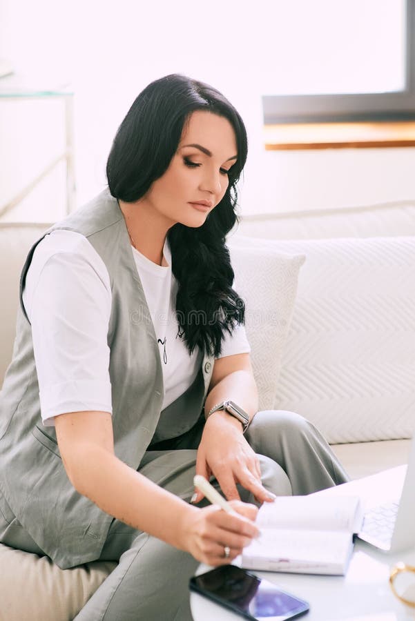 Woman Sitting on the Sofa and Making Notes in Her Notebook. Stock Image ...