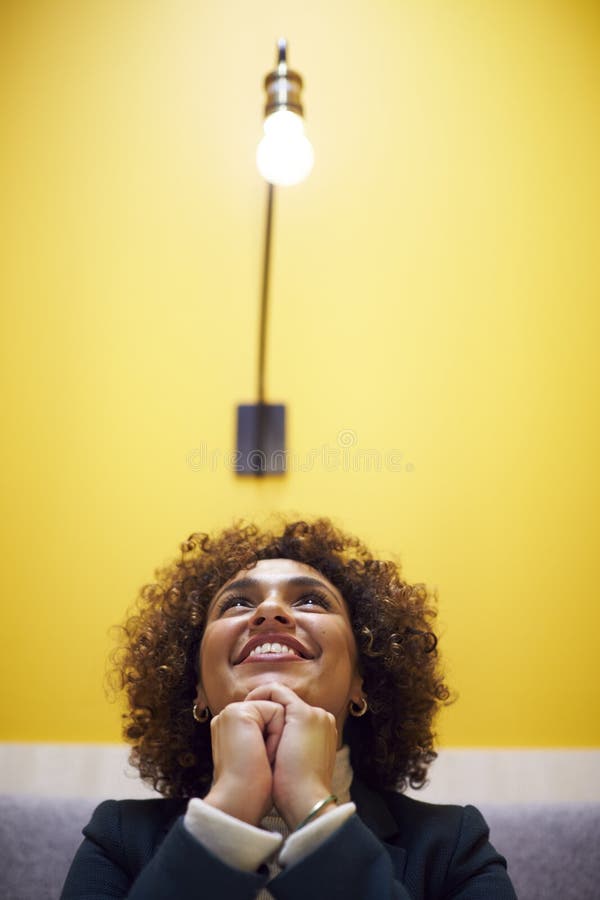 Woman Sitting Under Light Bulb in Office Suggesting Inspiration or Idea ...