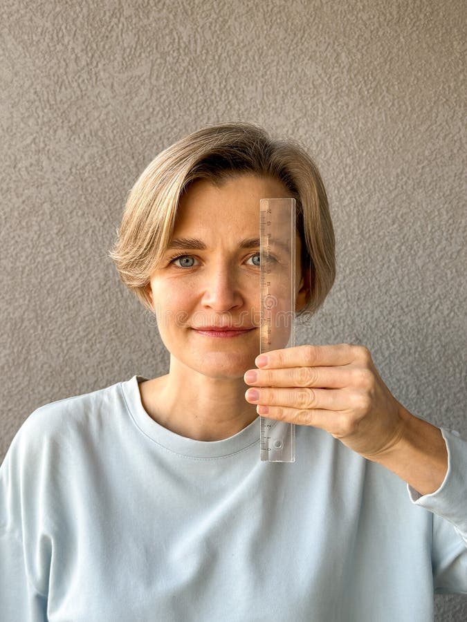 Woman Smiling while Holding a Transparent Ruler in Front of Her Face ...
