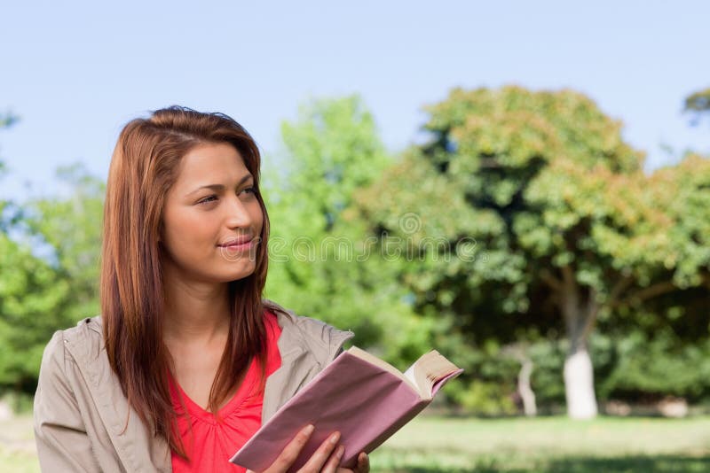Woman Smirking Towards the Side while Reading a Book Stock Photo ...