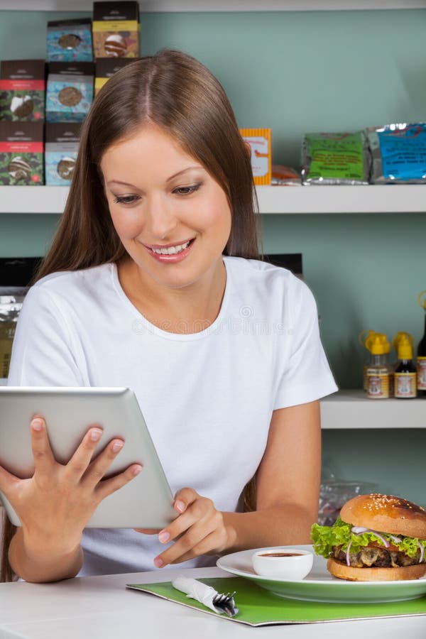 Woman with Snacks at Table Using Tablet in Store Stock Photo - Image of ...