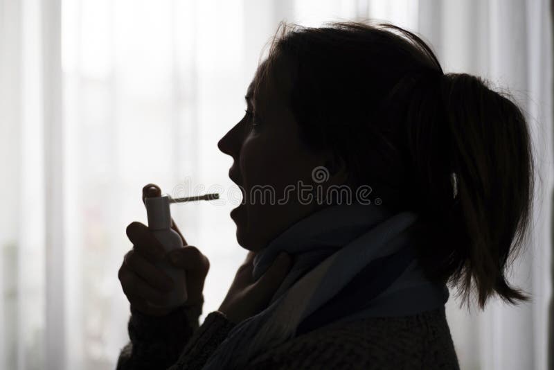 A Woman With A Sore Throat Sprays A Medicinal Aerosol Spray Down Her