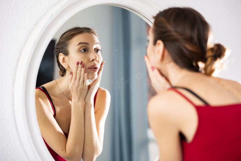 Woman Standing in Front of Mirror and Looking at Her Face Stock Photo ...