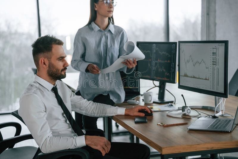 Woman is Standing and Holding Documents. Two Employees are Working in ...