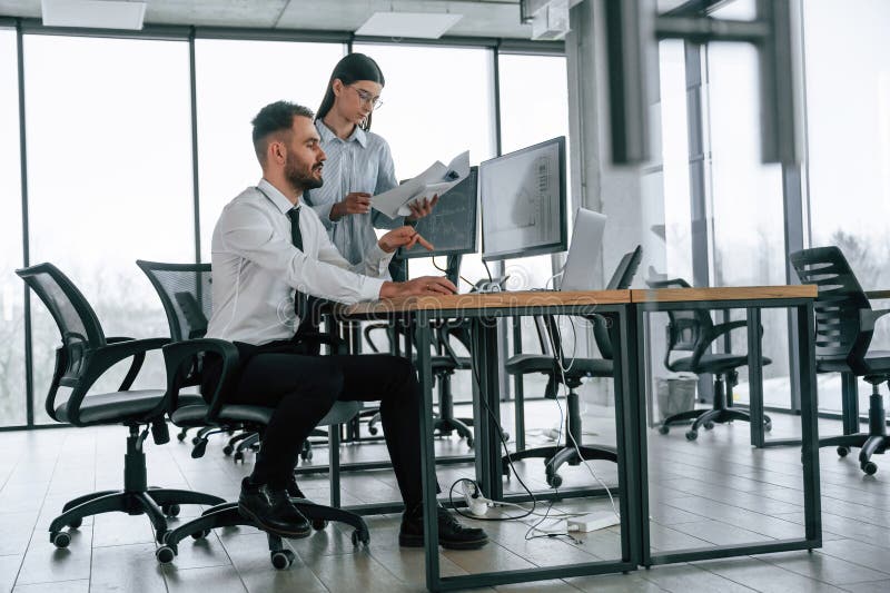 Woman is Standing and Holding Documents. Two Employees are Working in ...