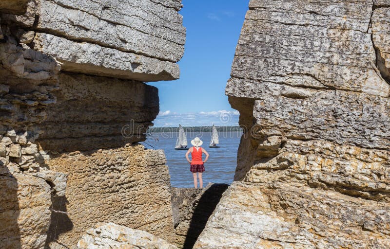Woman Standing between Two Rock Cliffs Watching Sailboats Float by ...