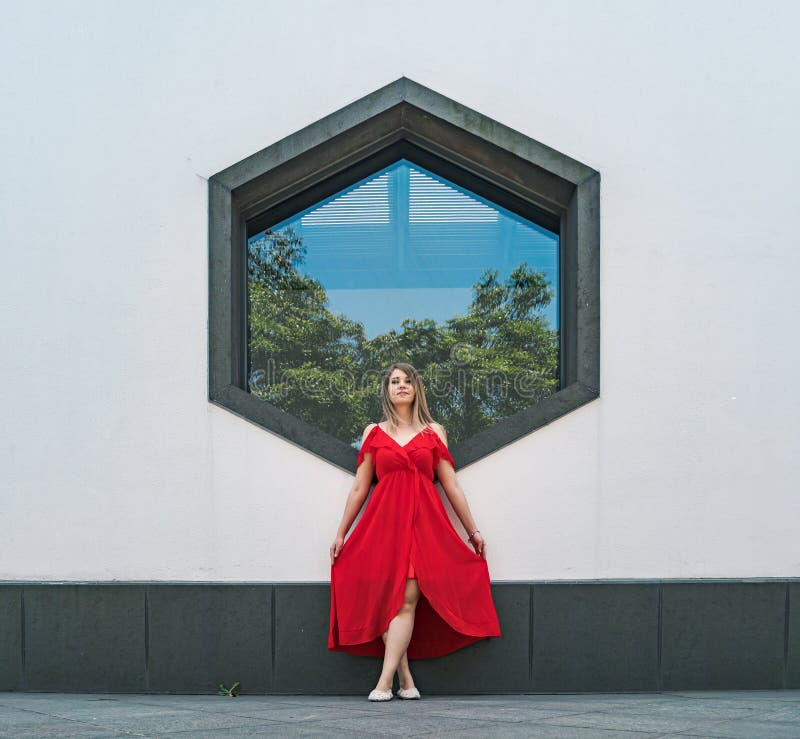 A Woman Stands Elegantly in a Flowing Red Dress, Striking a Pose in ...