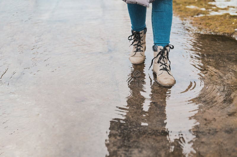 A Woman Steps into a Puddle. Splashes of Water Scatter from Under the ...
