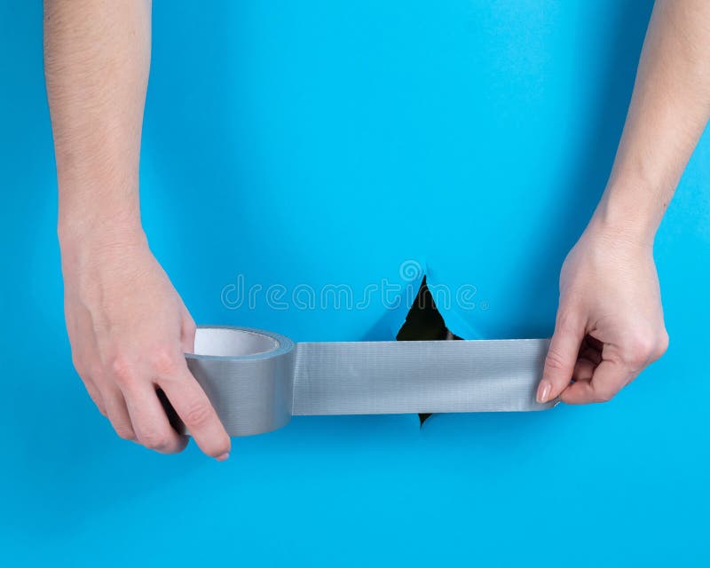 Woman Sticking Silver Tape on a Hole on a Blue Background. Stock Photo ...