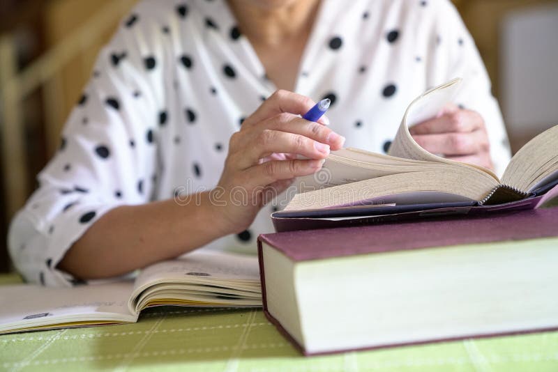Woman Reading a Book while Doing Her Assignment Stock Image - Image of ...