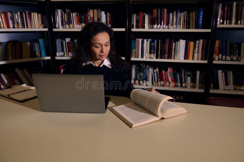 Woman Studying in a Library with a Laptop and Open Book Stock Photo ...