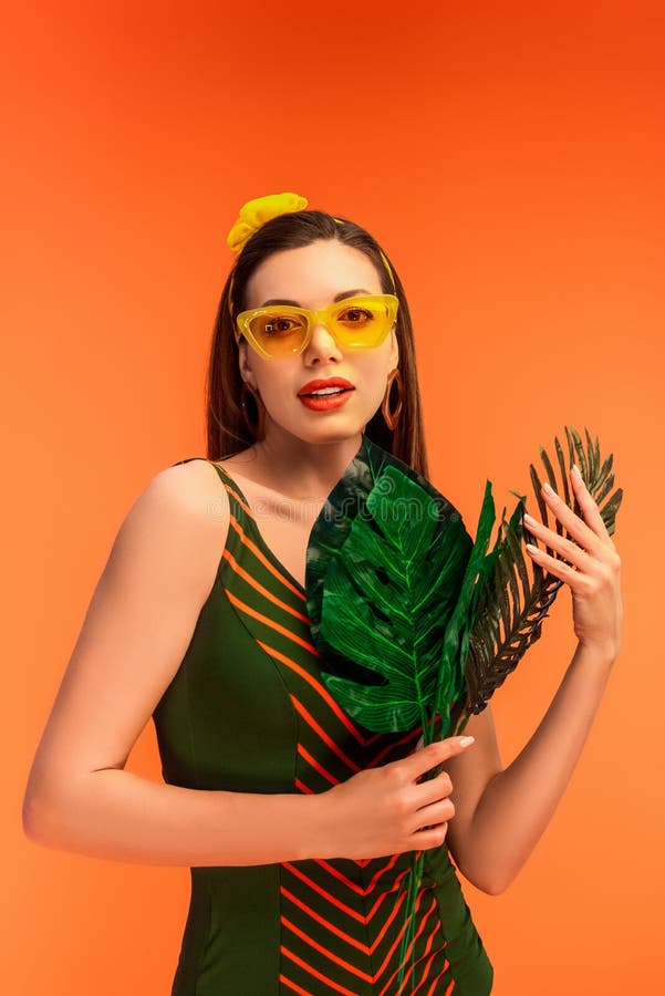 Woman In Sunglasses Holding Green Leaves And Looking At Camera Stock
