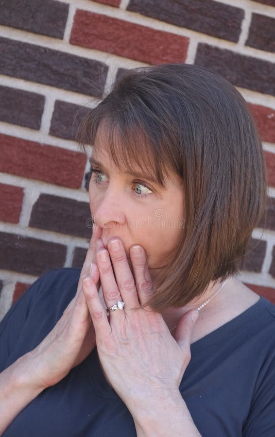 Woman with Surprised Look and Hands Over Face Against a Brick Wall ...