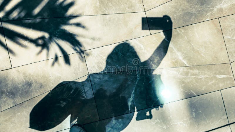 A Woman Takes a Selfie and a Shadow Silhouette of Her is on the Ground ...