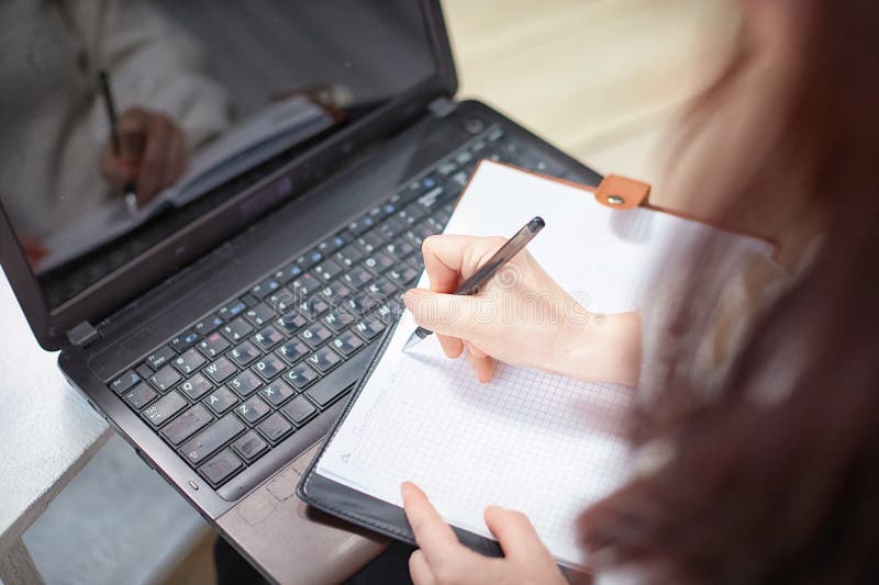 Woman Taking Notes beside Laptop in Bright Indoor Setting. a Focused ...