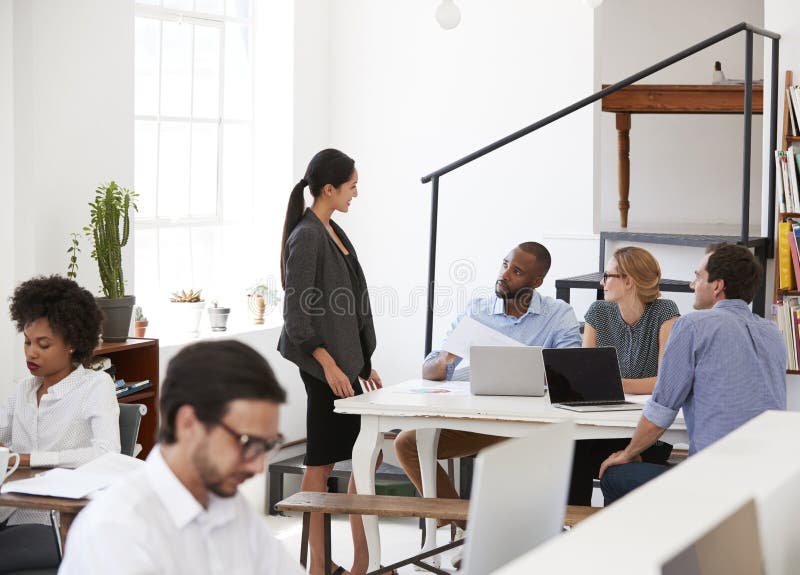 Woman Talking with Colleagues at a Desk in Open Plan Office Stock Photo ...